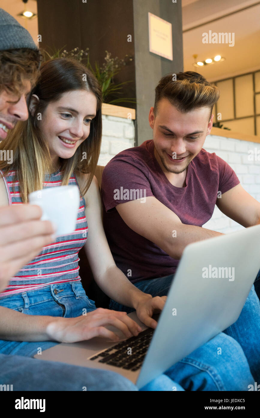 Three friends sharing laptop in a cafe Stock Photo - Alamy