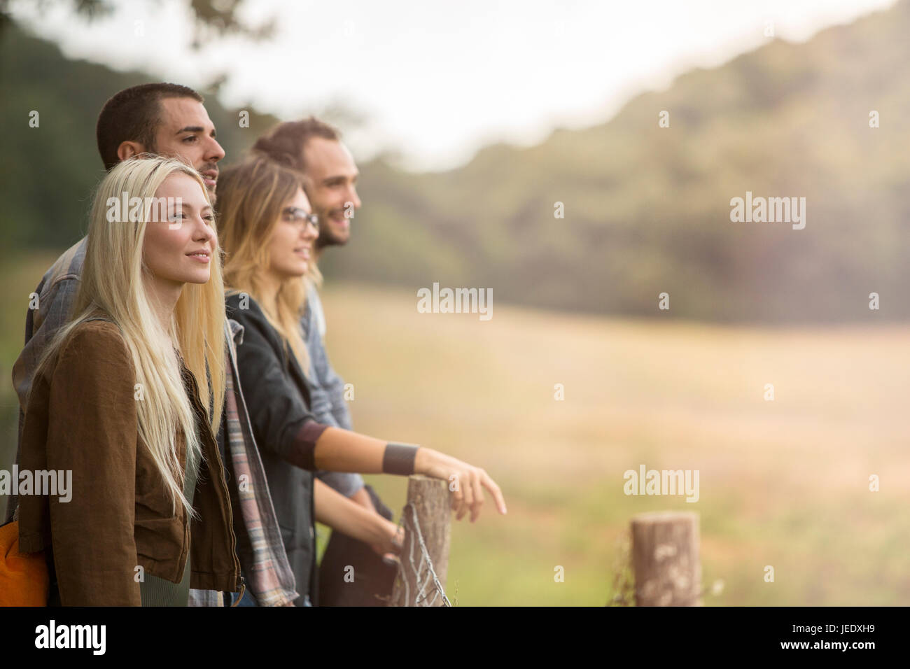 Four friends looking out at a field Stock Photo - Alamy