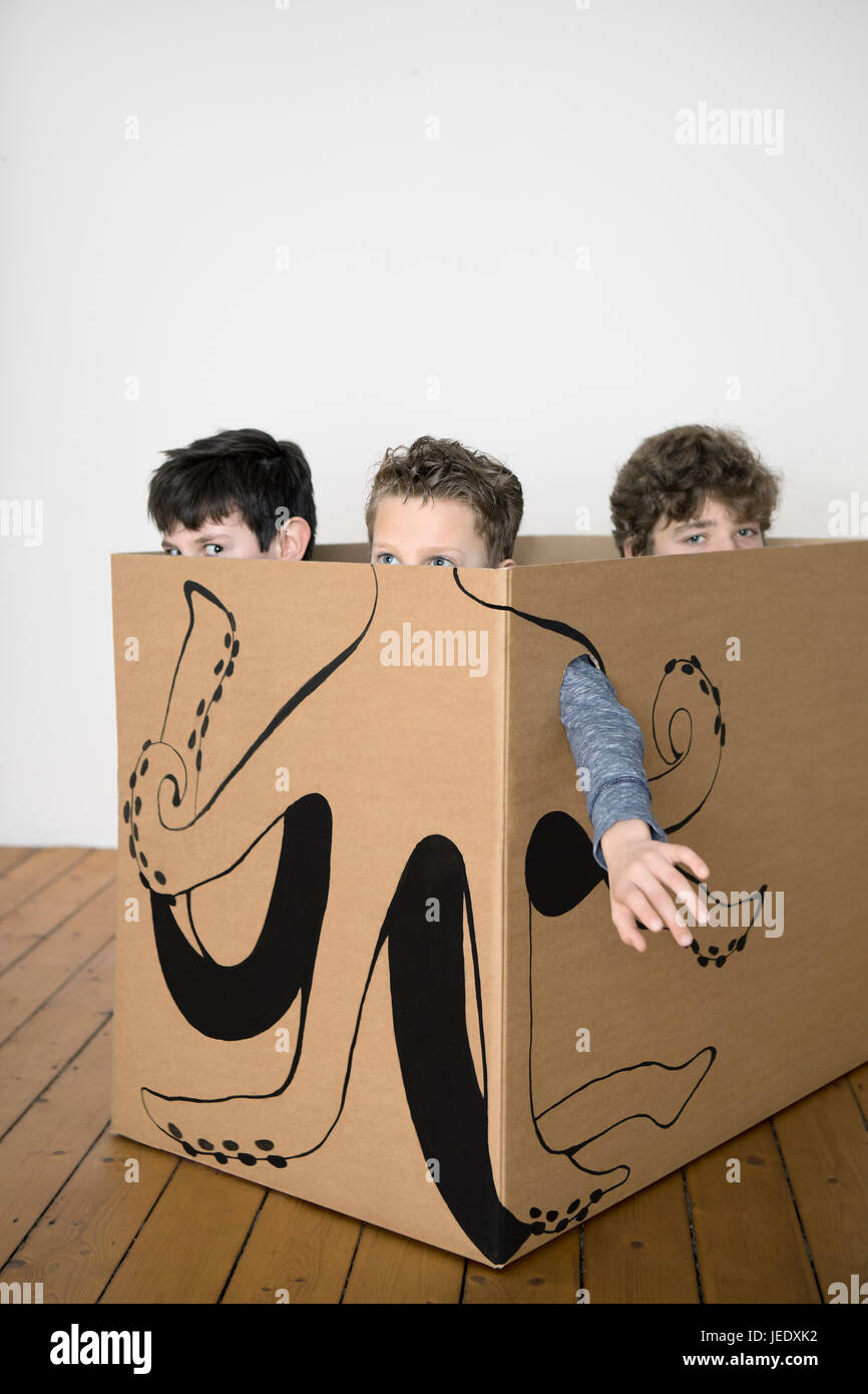 Three boys inside a cardboard box painted with an octopus Stock Photo ...