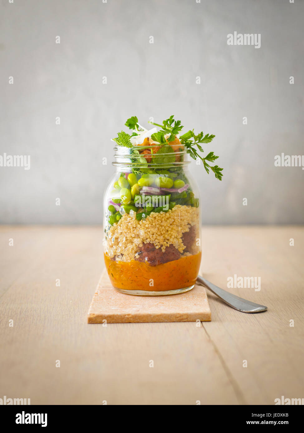 Preserving jar of quinoa salad with vegetables, coconut chips and meat ...