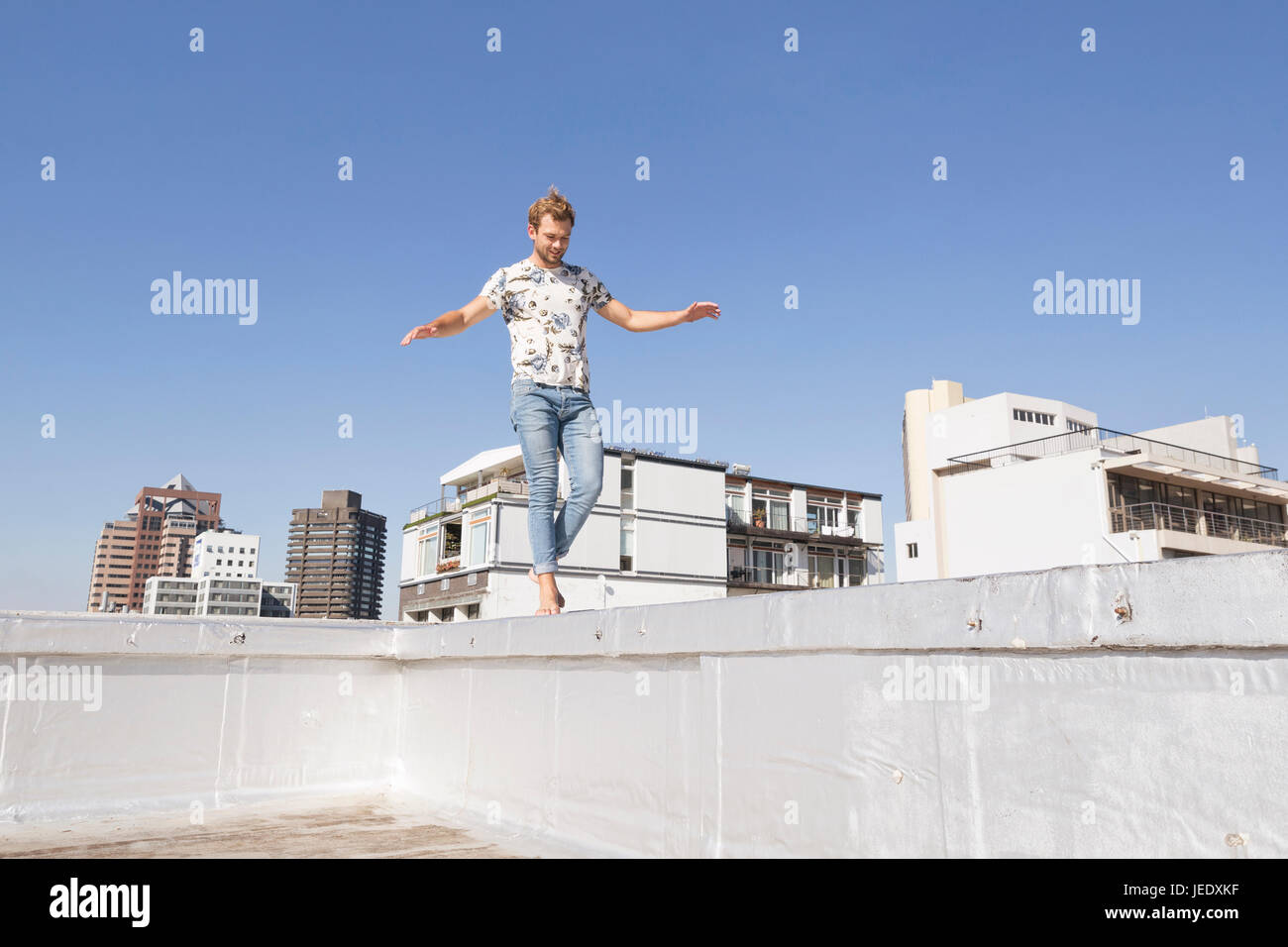 Barefooted man balancing on balustrade of a rooftop terrace Stock Photo ...