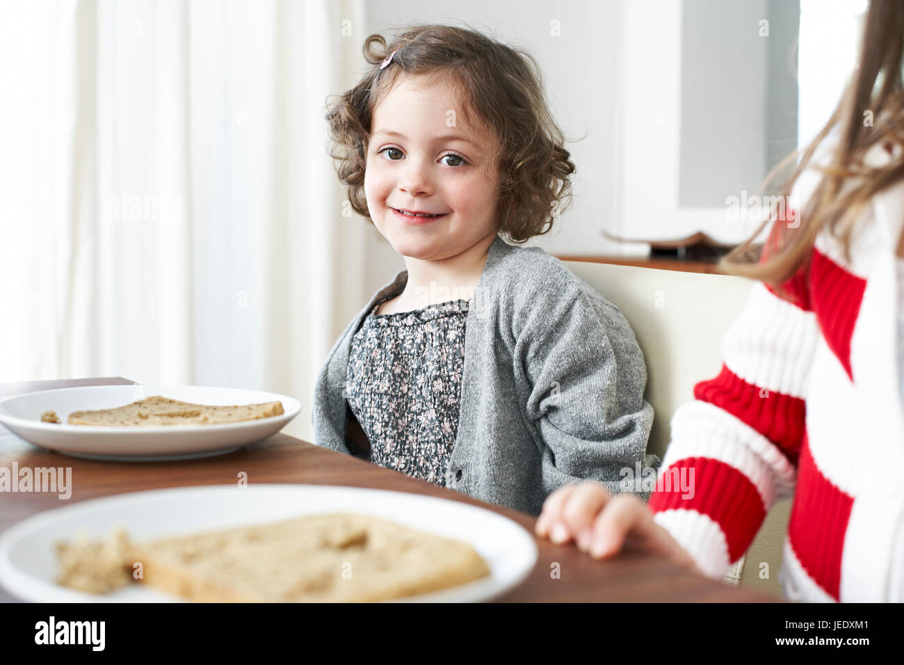Portrait of smiling little girl at dining table Stock Photo - Alamy