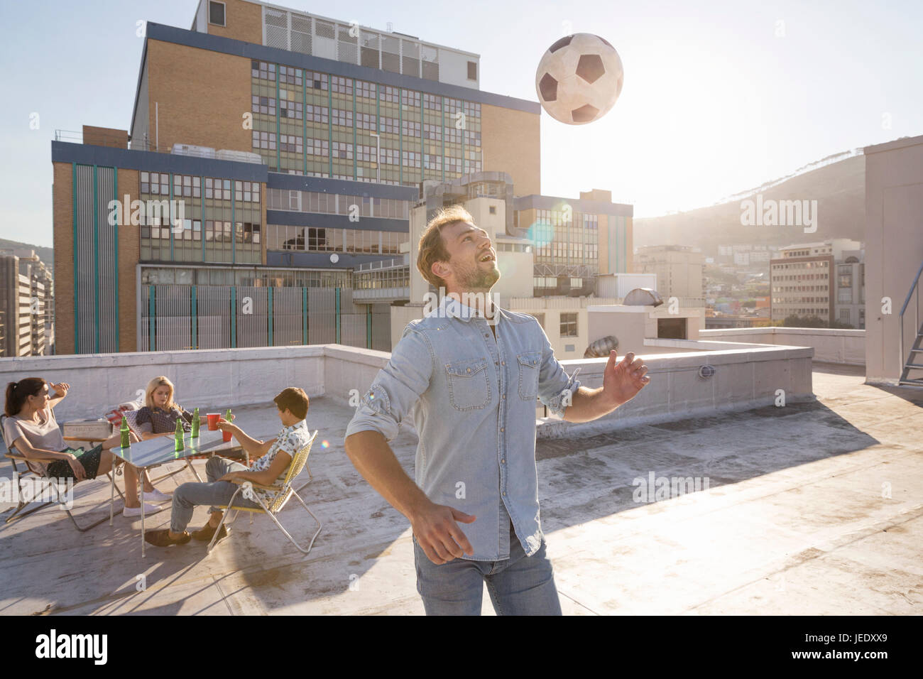 Friends meeting on rooftop terrace in summer, playing football Stock ...