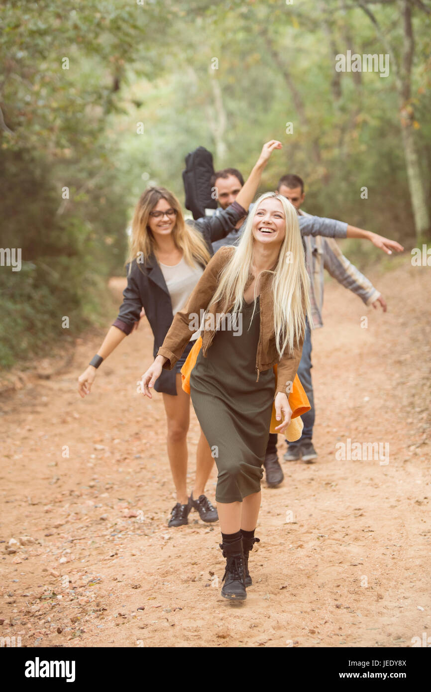 Four happy friends having fun on path in the forest Stock Photo - Alamy