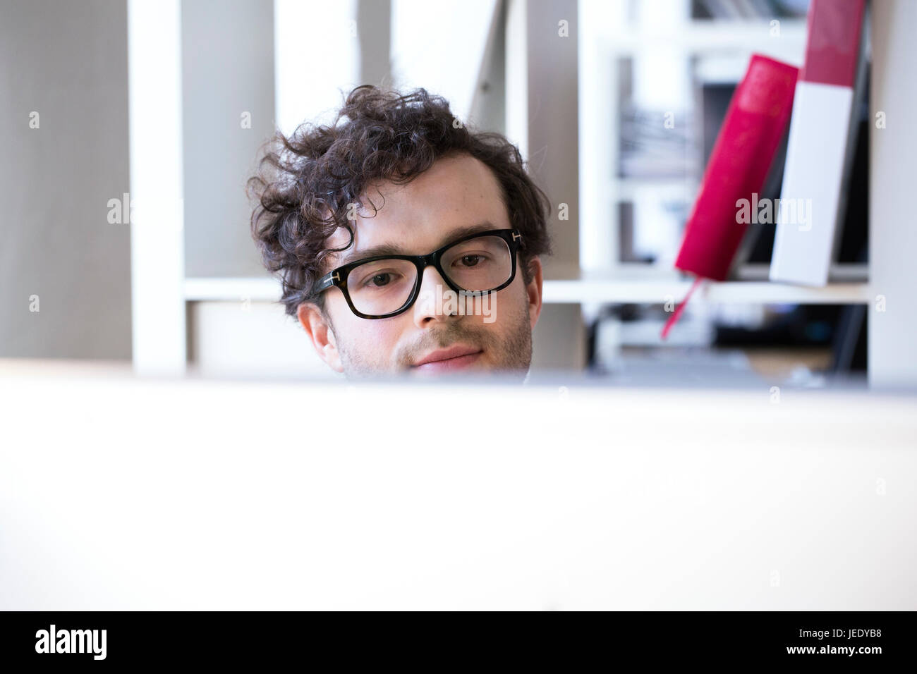 Confident man in office looking at computer screen Stock Photo - Alamy
