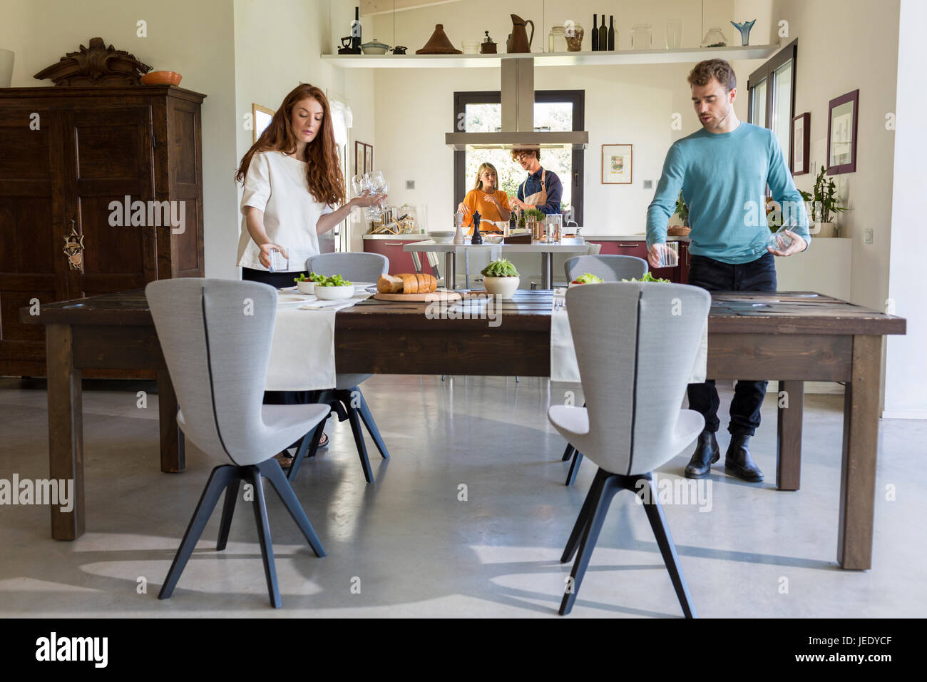 Two couples cooking and laying table together Stock Photo - Alamy