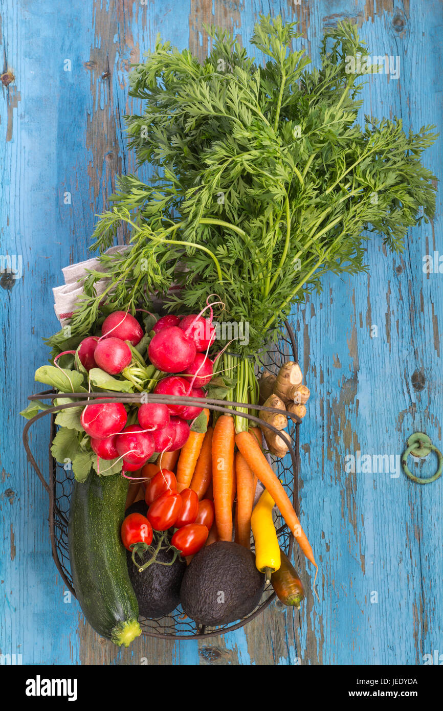 Wire basket with various vegetables on blue wood Stock Photo - Alamy