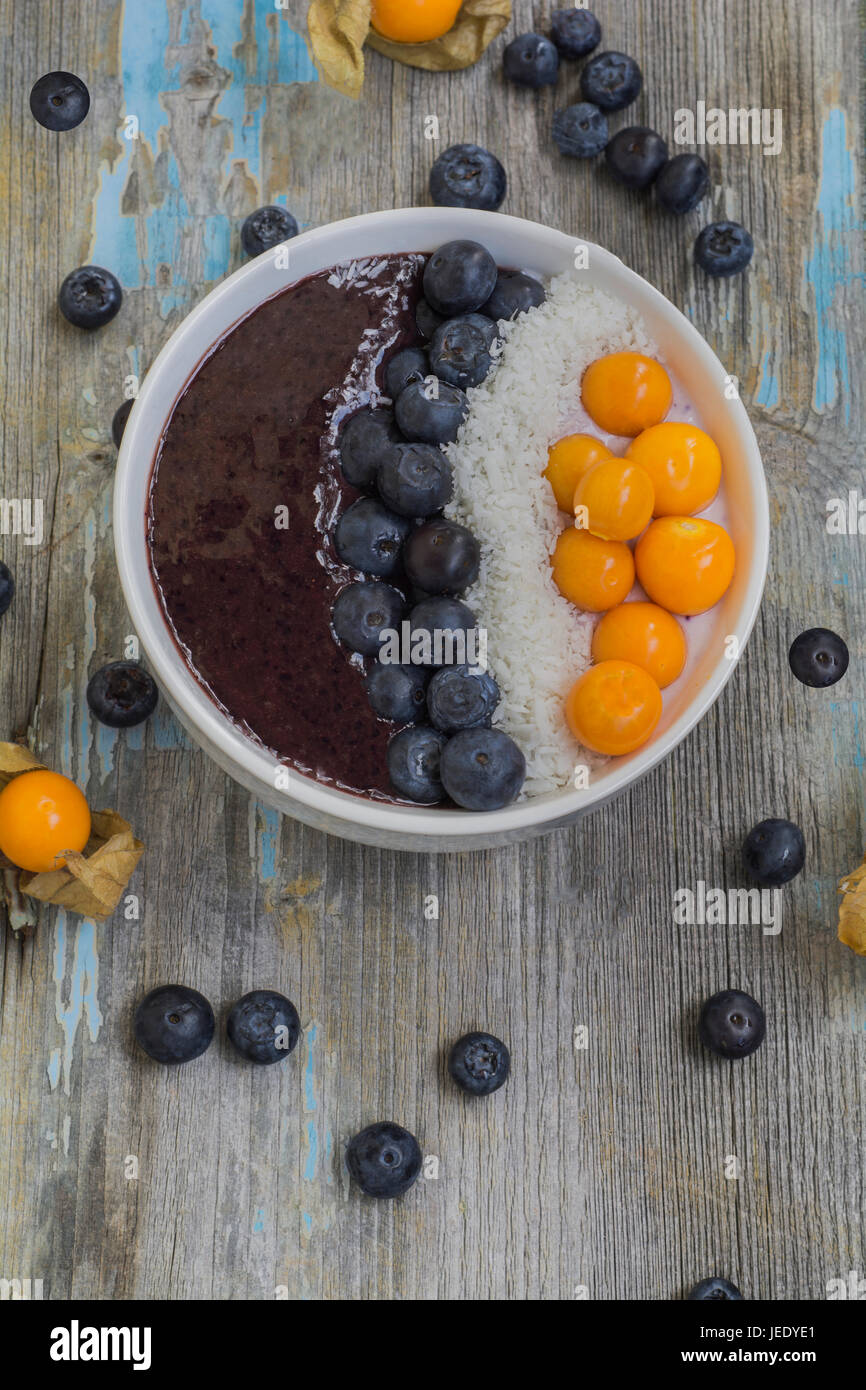 Bowl of joghurt with blueberry mush, coconut flakes, physalis and ...