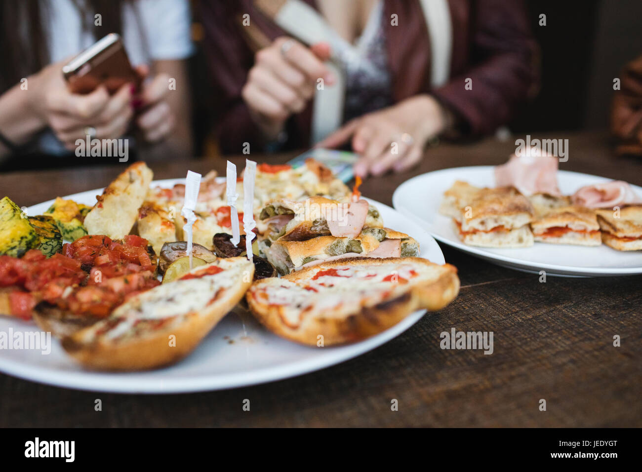 Plates with appetizers and two women with cell phones in background ...