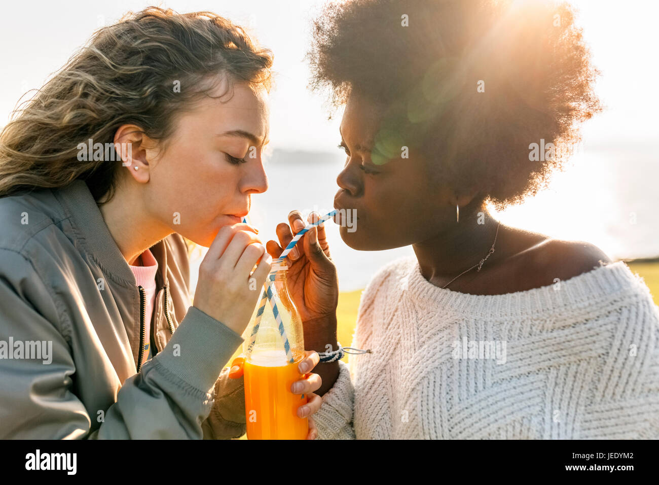 Two best friends drinking orange juice outdoors Stock Photo - Alamy