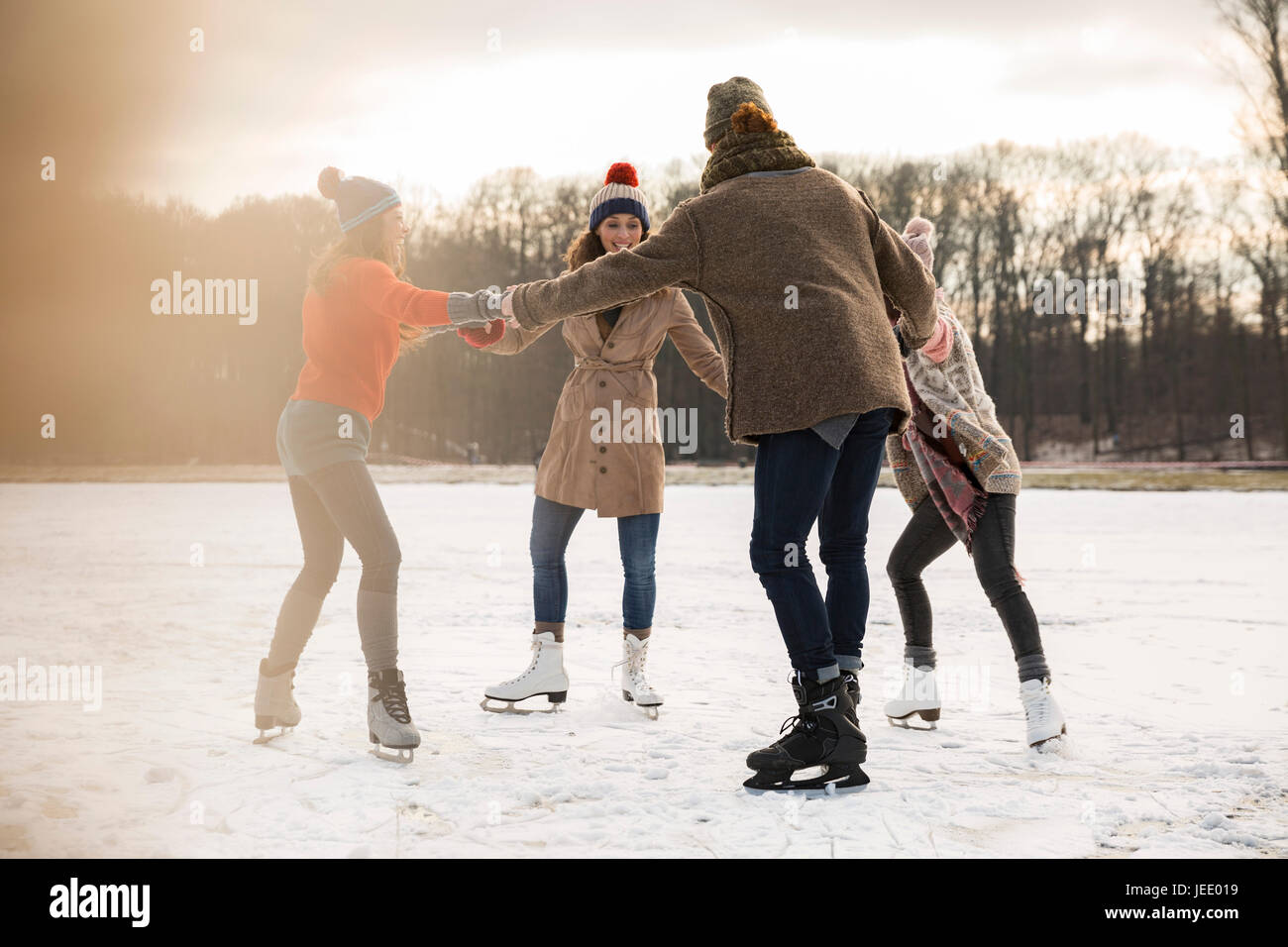 Friends ice skating in a circle on frozen lake Stock Photo - Alamy