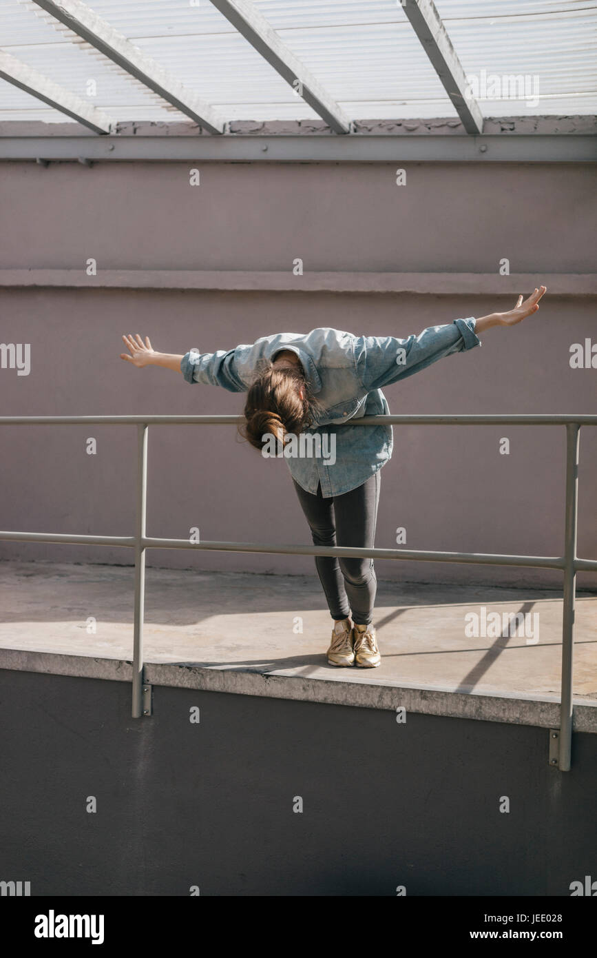 Young woman bending over railing with arms outstretched Stock Photo - Alamy