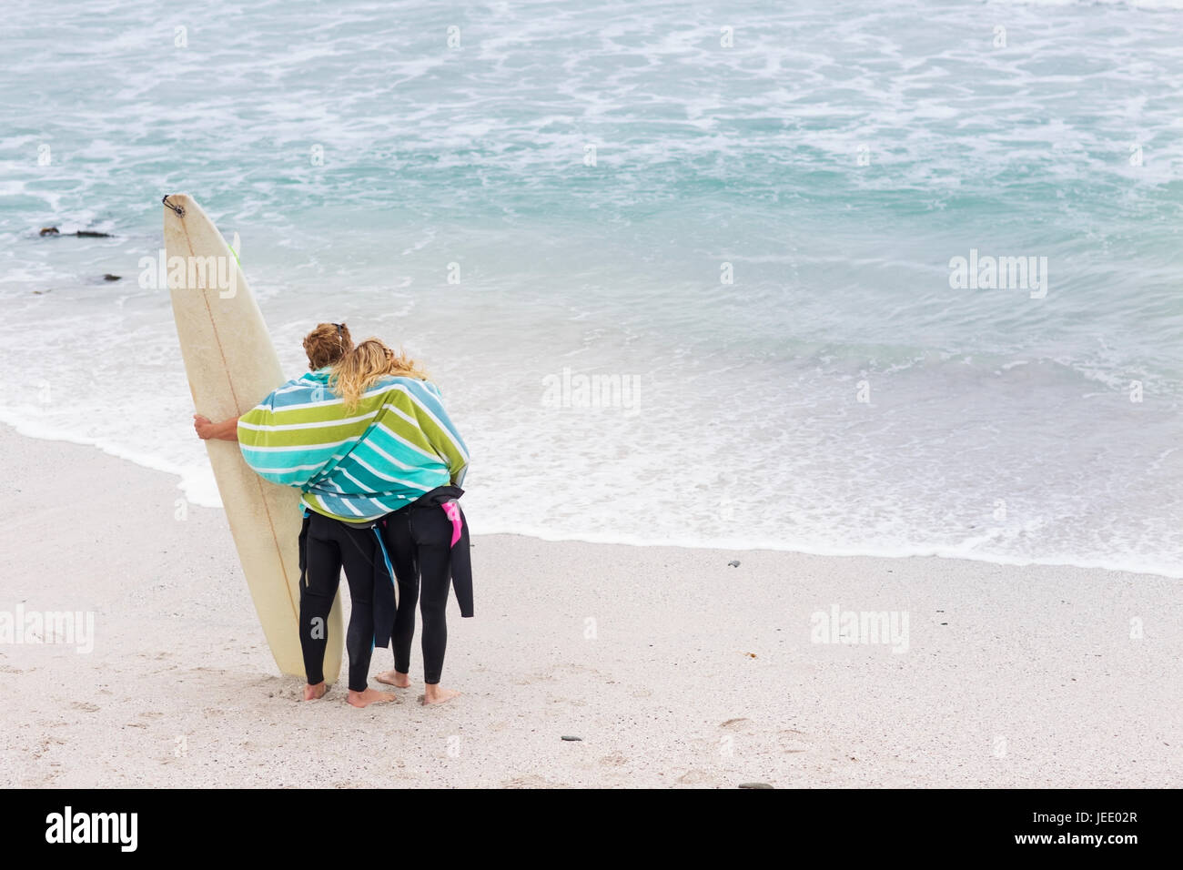 Couple on the beach with surfboard Stock Photo - Alamy