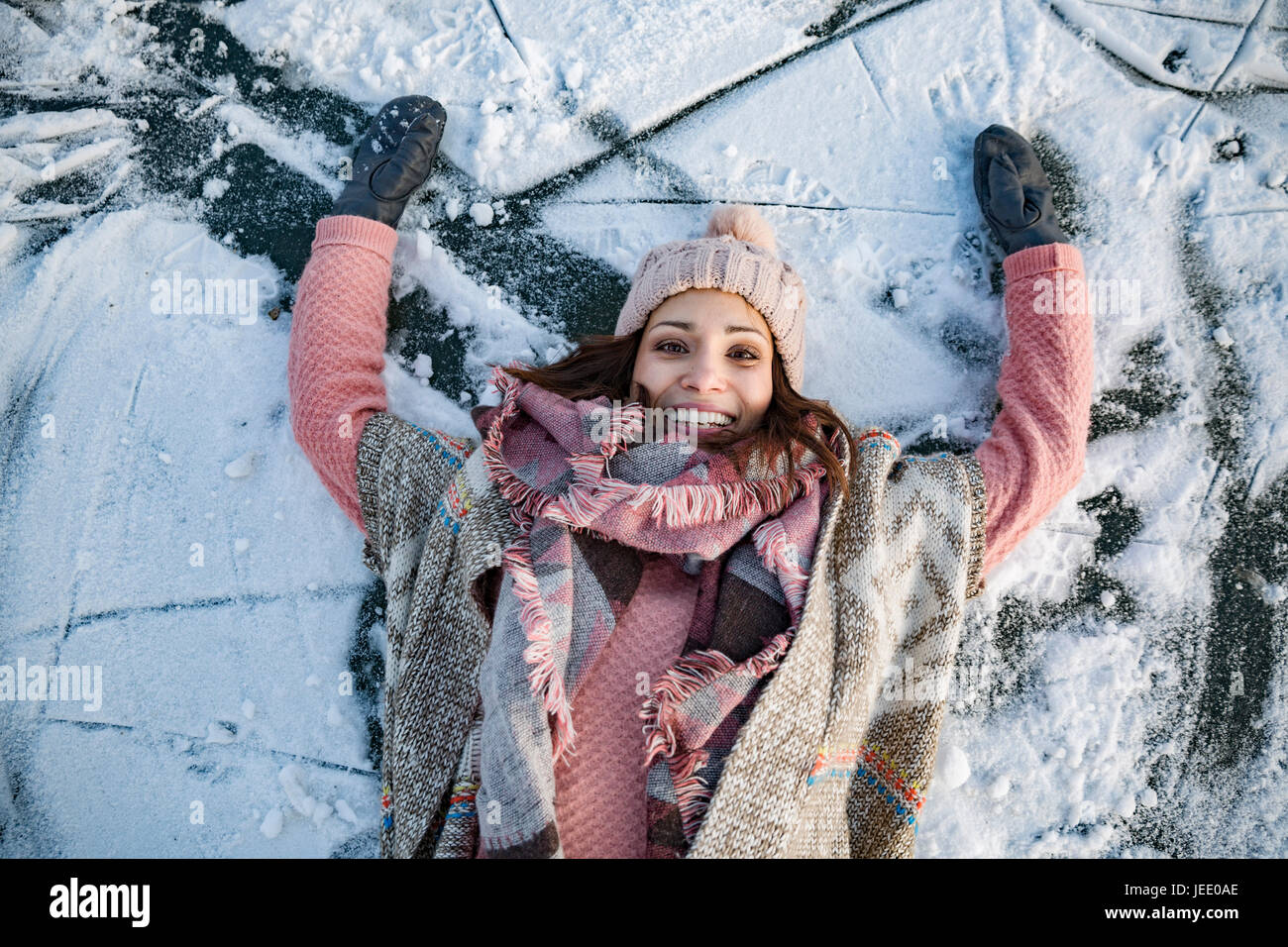 Portrait of happy woman lying down on frozen lake surface Stock Photo ...