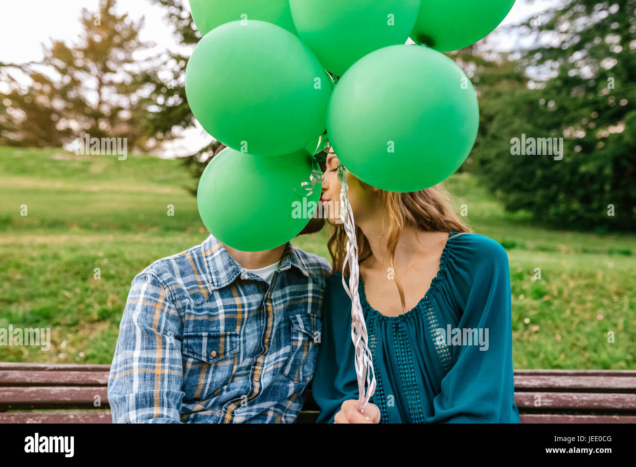 Young couple kissing behind green balloons Stock Photo - Alamy