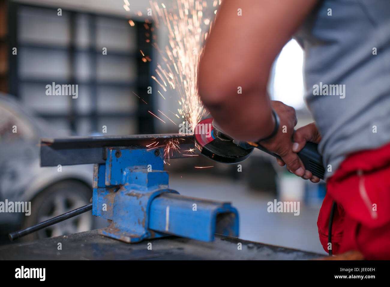 Mechanic using angle grinder in car workshop Stock Photo - Alamy