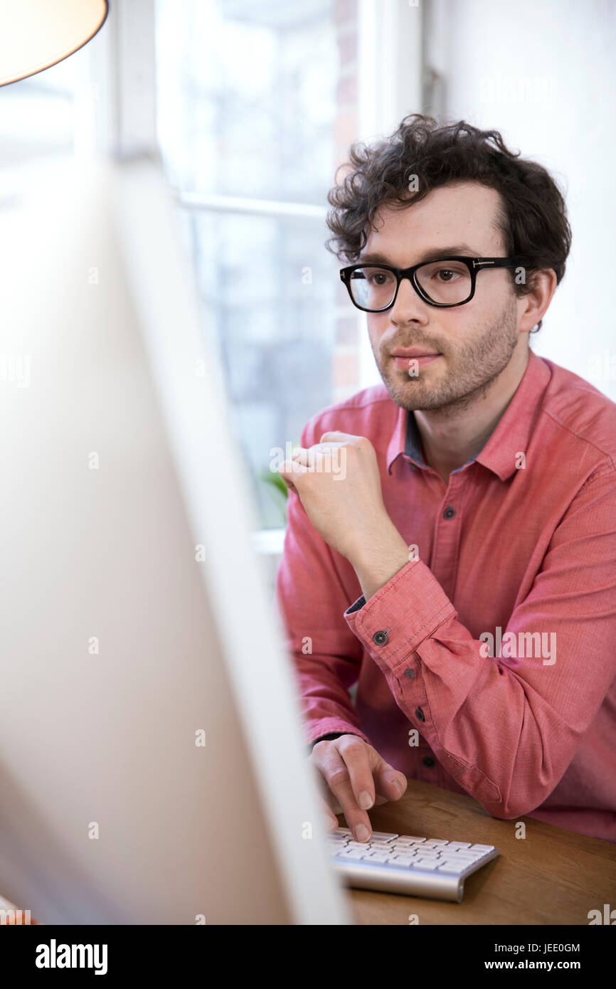 Confident man in office looking at computer screen Stock Photo - Alamy