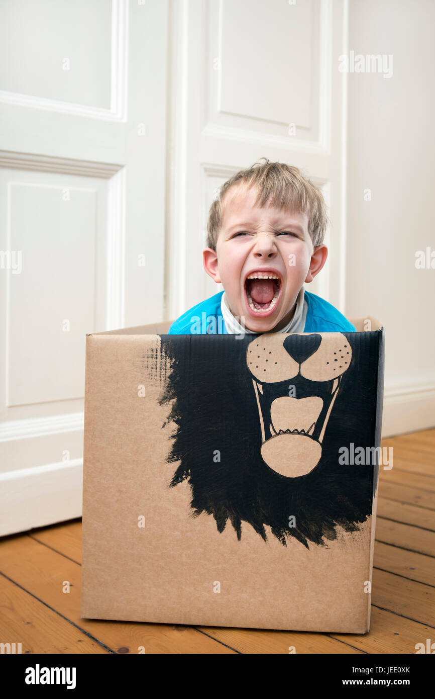 Roaring boy inside a cardboard box painted with a lion Stock Photo - Alamy