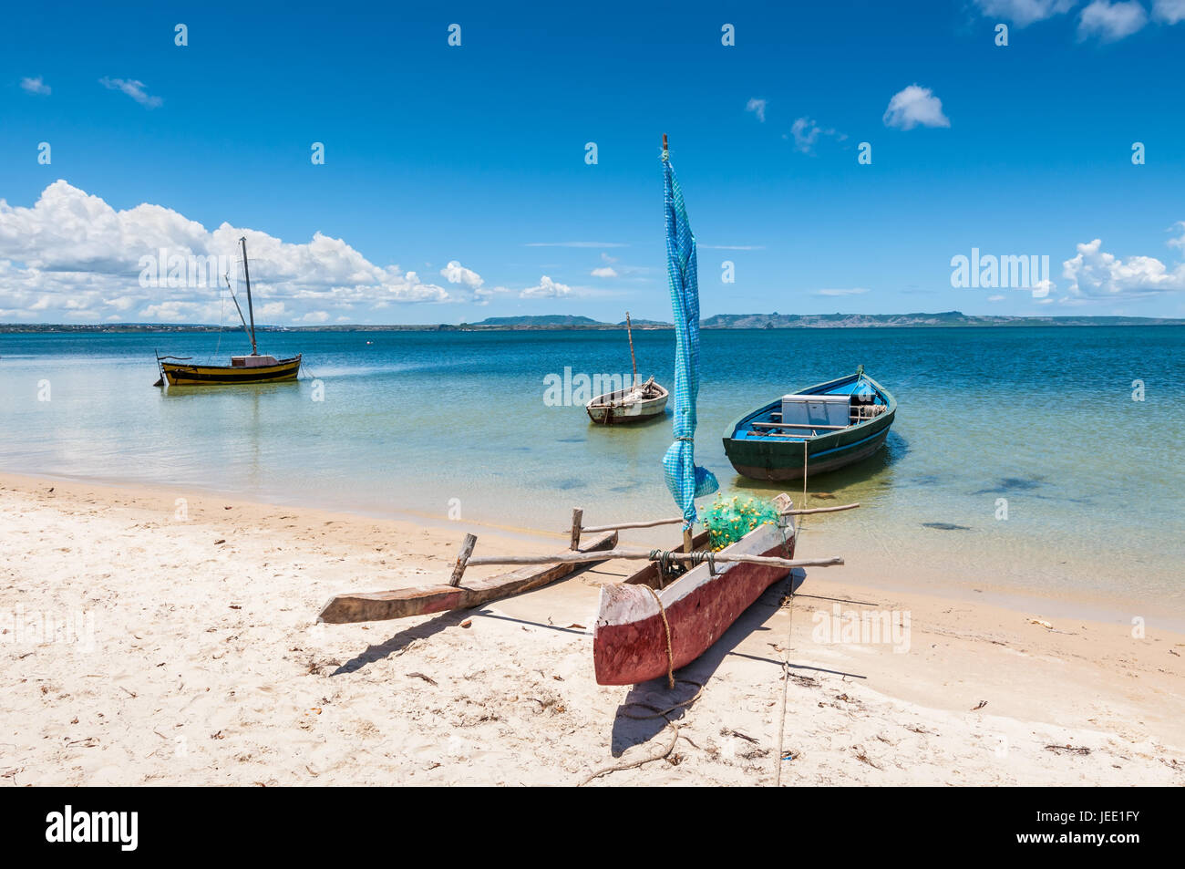 Malagasy outrigger pirogue with sail and boats on the white beach ...