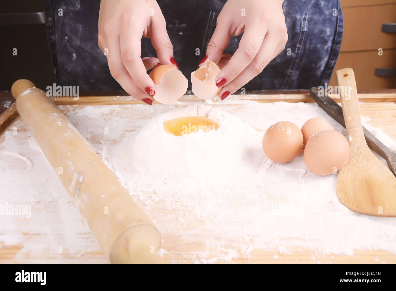 Close-up of woman chef breaking an egg to make a dough. Cooking concept ...