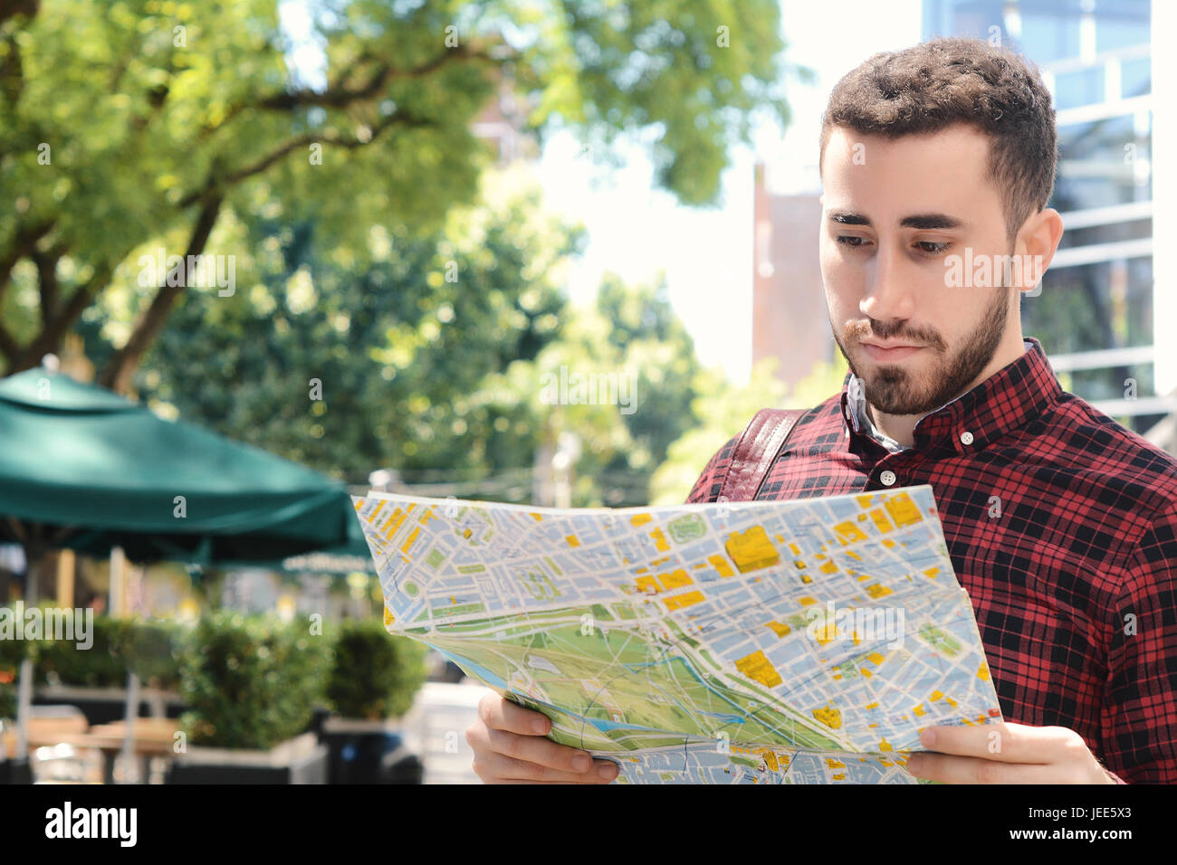Portrait of a young handsome tourist man looking at a map. Tourism ...