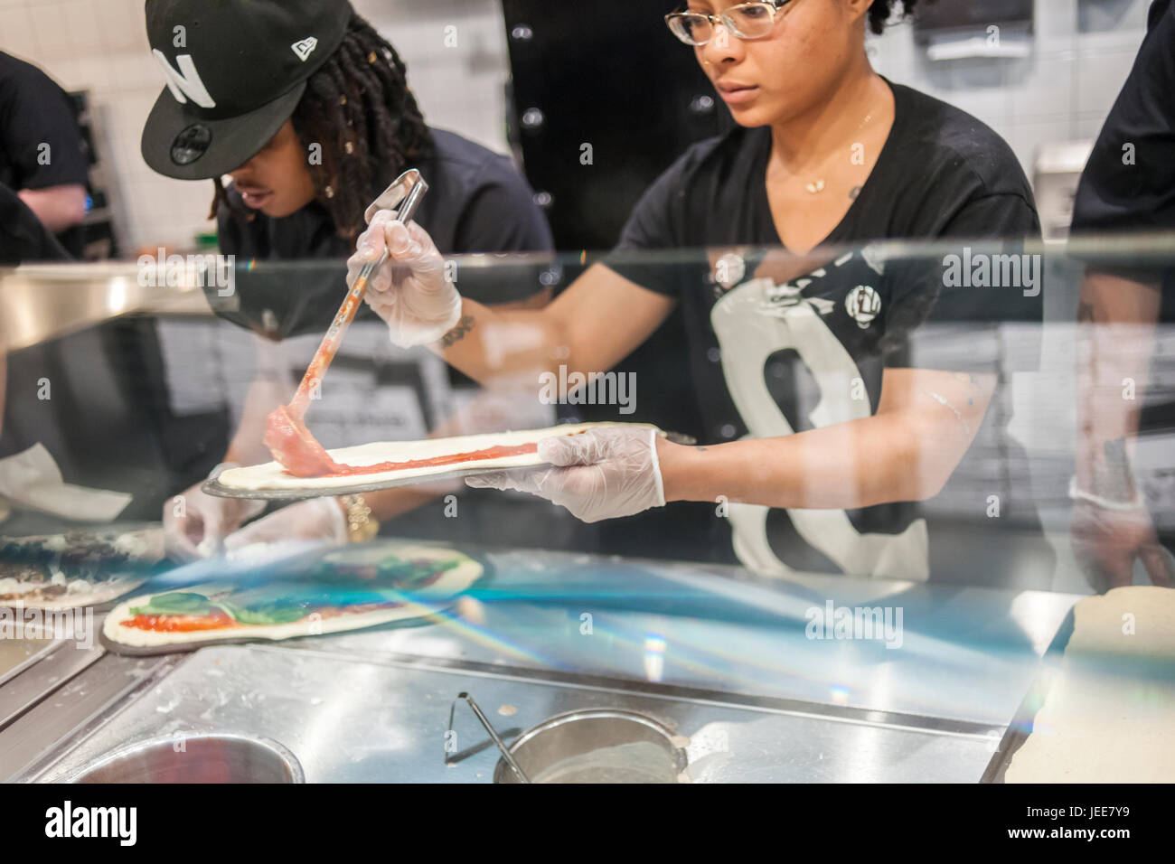 Employees construct a pizza right before the customers' eyes in ...