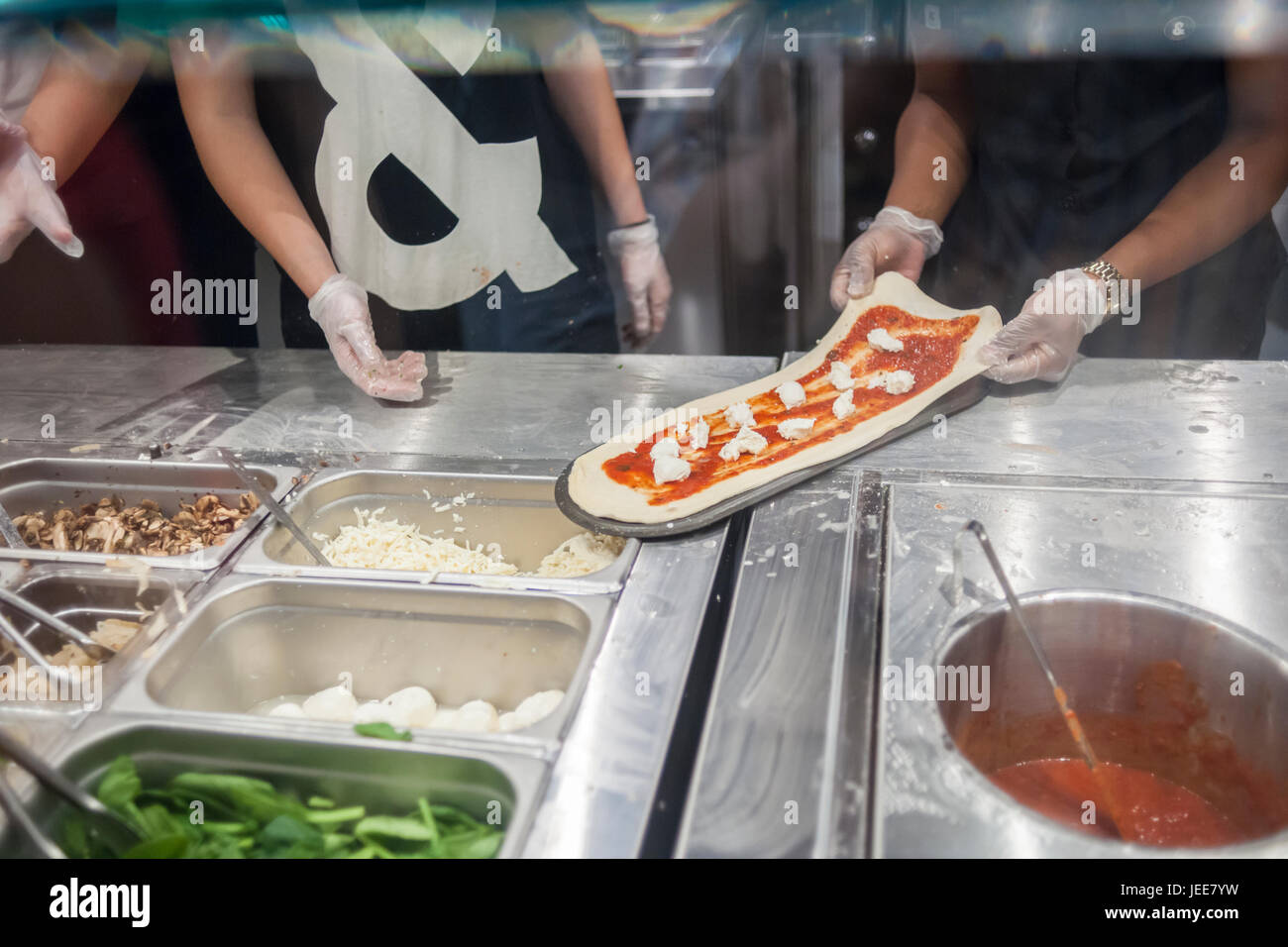 Employees construct a pizza right before the customers' eyes in ...