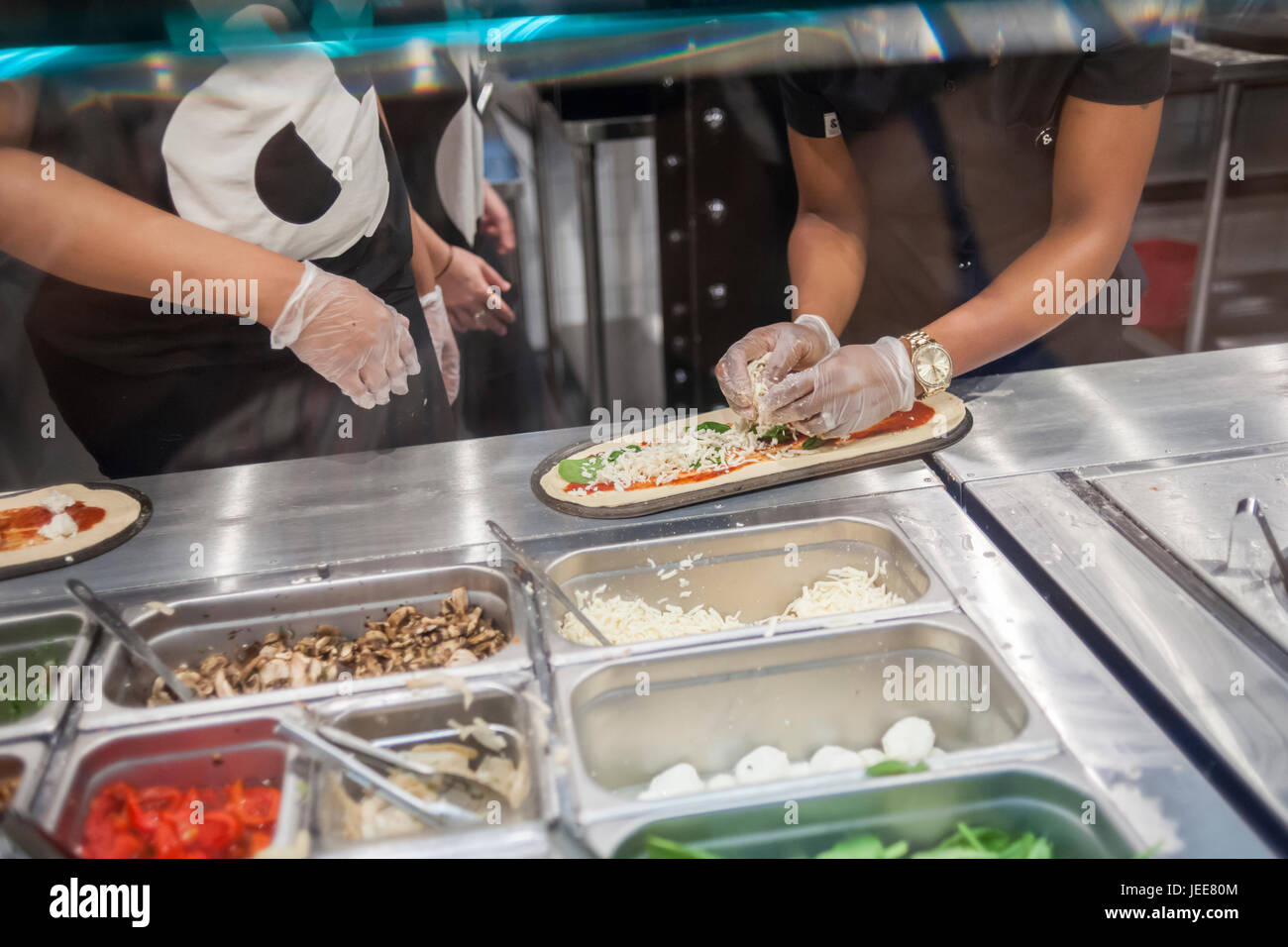 Employees construct a pizza right before the customers' eyes in ...
