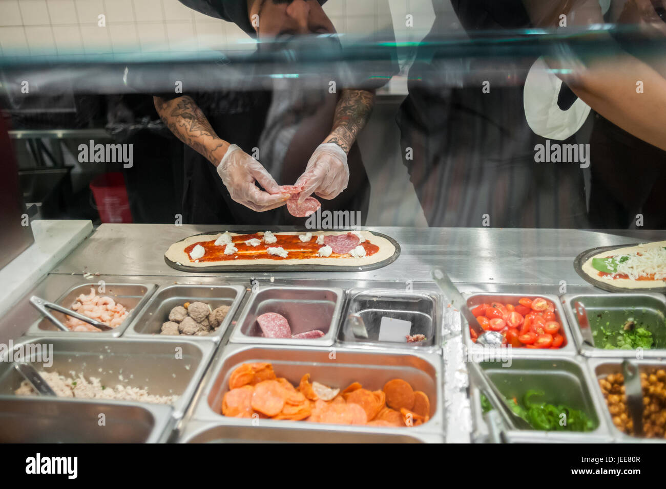 Employees construct a pizza right before the customers' eyes in ...