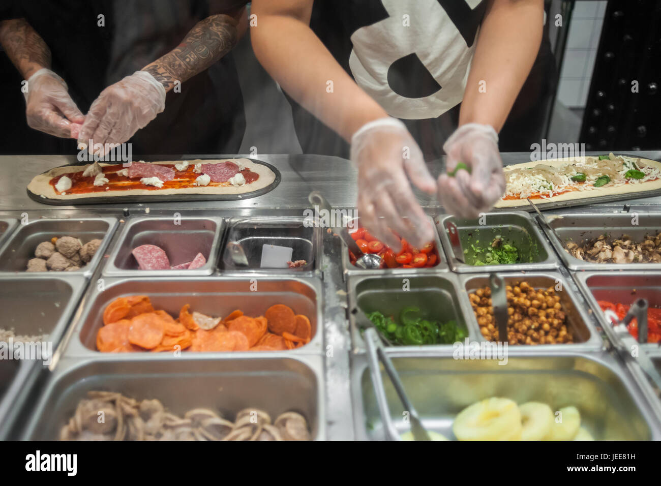 Employees construct a pizza right before the customers' eyes in ...