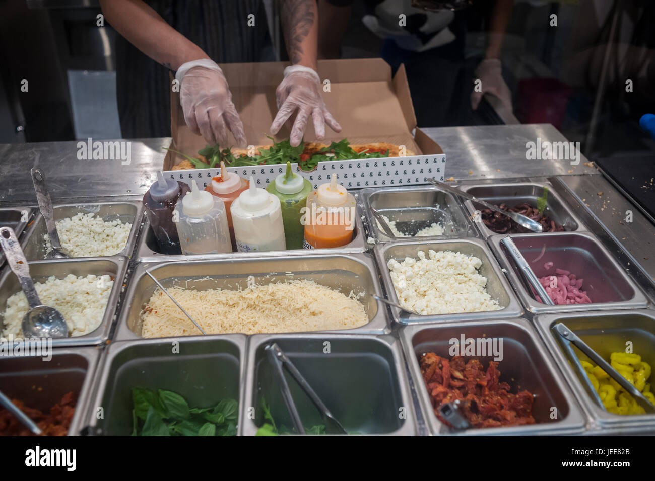 Employees construct a pizza right before the customers' eyes in ...