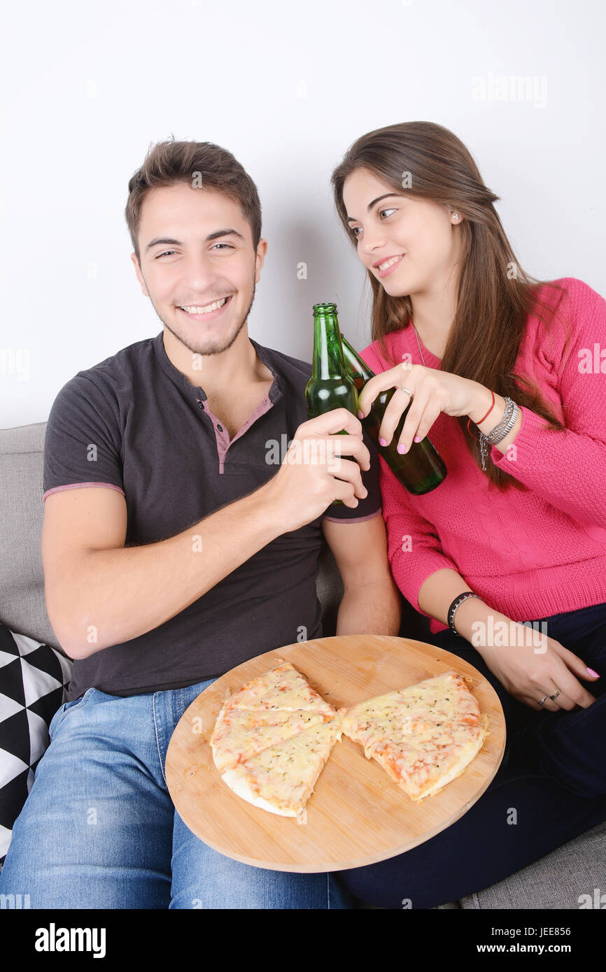 Beautiful young couple drinking beer and eating pizza. Indoors Stock ...