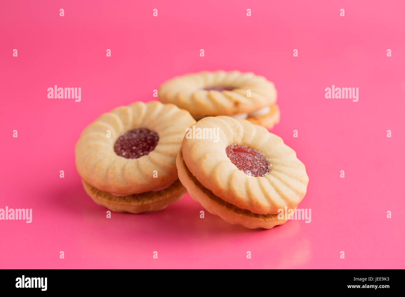Sweet biscuits with jam on pink background Stock Photo - Alamy