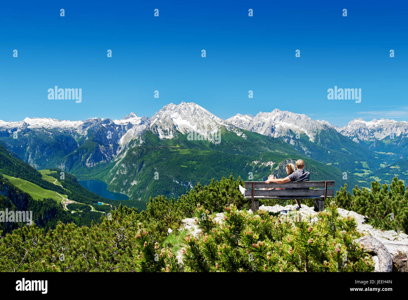 Couple sitting on a bench in front of the alps enjoying the mountain ...