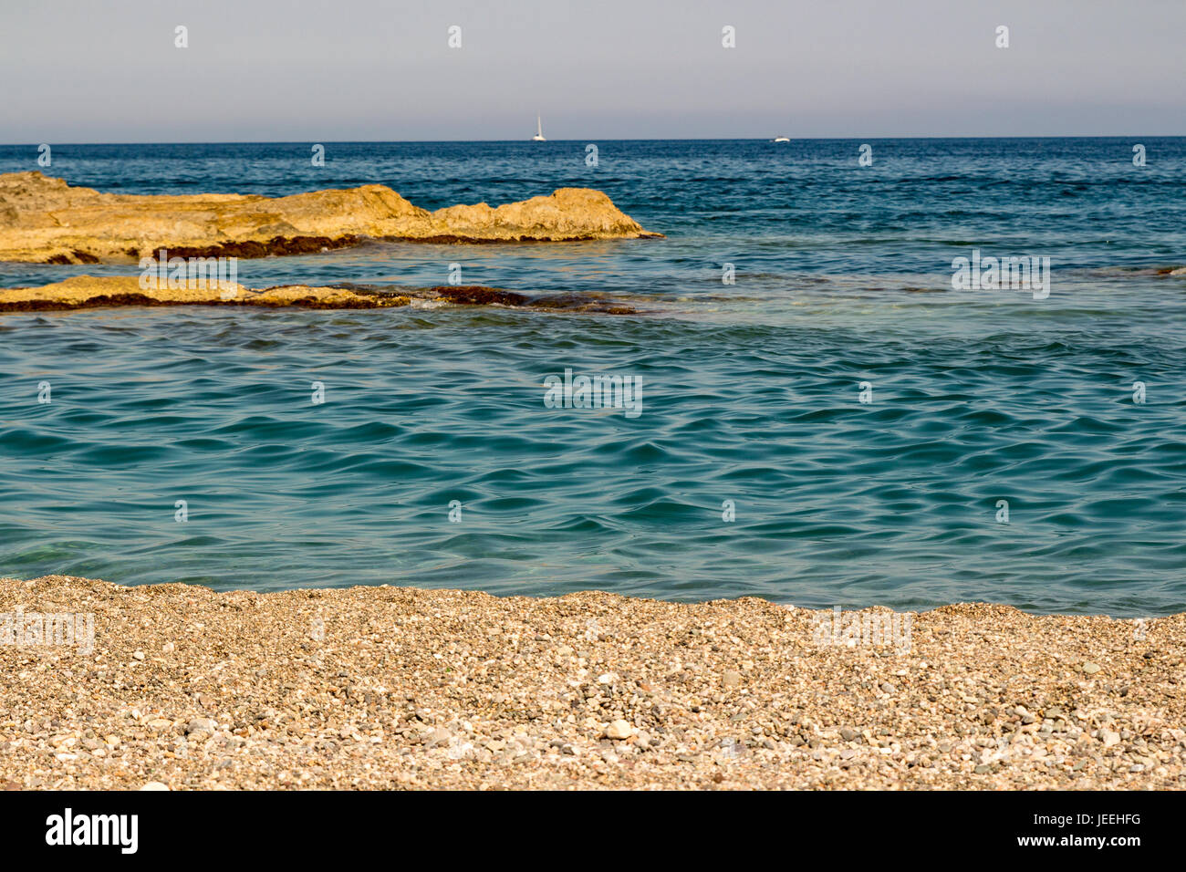 Sand the rocks and a blue Mediterranean sea Stock Photo - Alamy