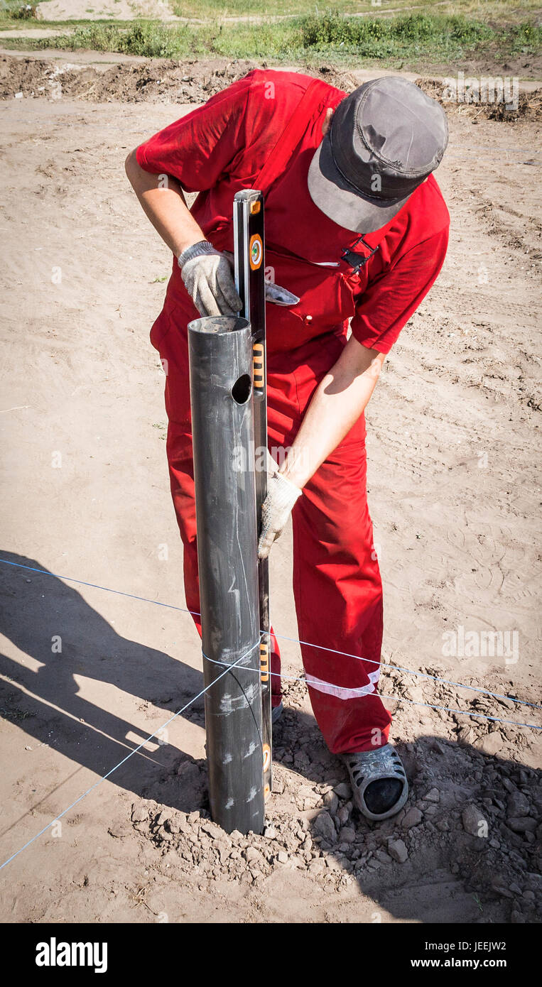 The worker measures the verticality of the pile at a construction site ...
