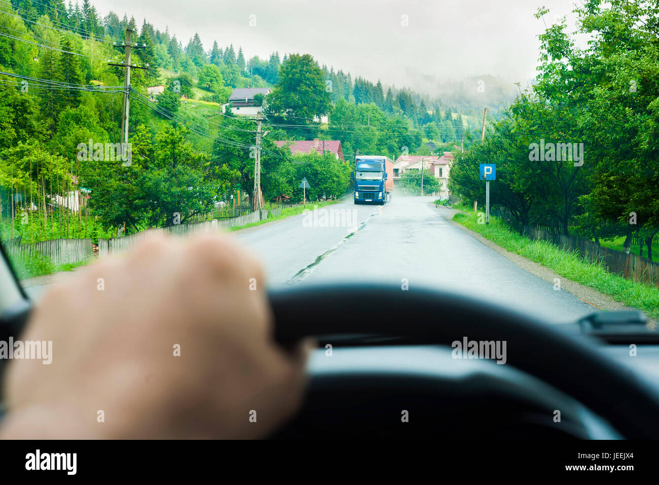 view of road and hand on wheel of car driving, focus on background ...