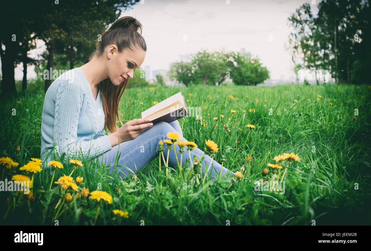 portrait of a beautiful young caucasian woman reading a book outdoor ...