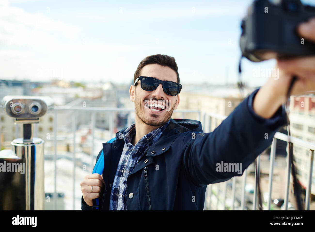 Smiling traveler with camera making photo of himself Stock Photo - Alamy