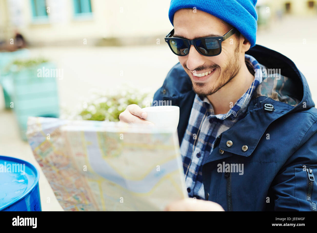 Happy young explorer looking at map of location Stock Photo - Alamy