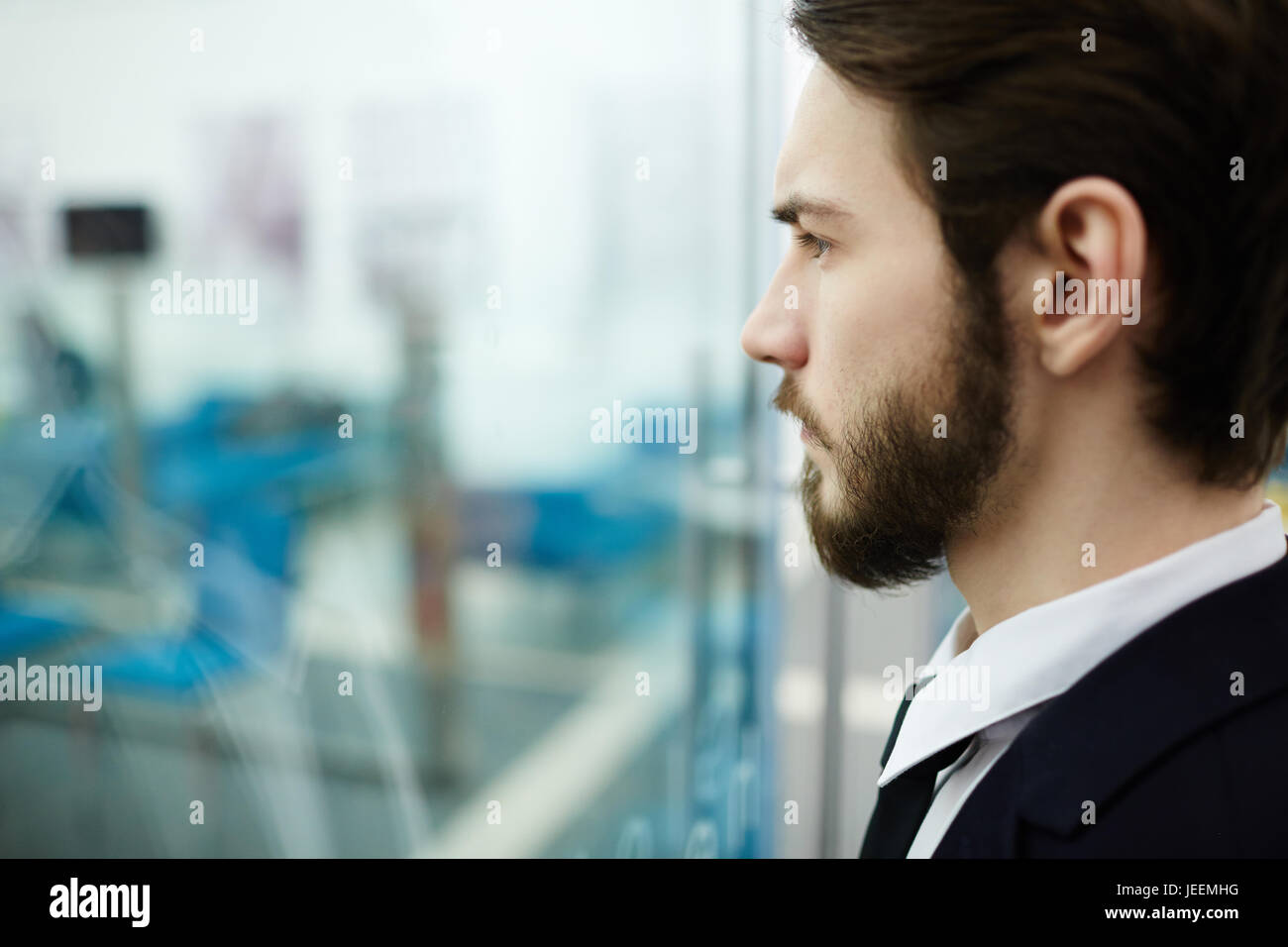 Serious employee looking through office window Stock Photo - Alamy