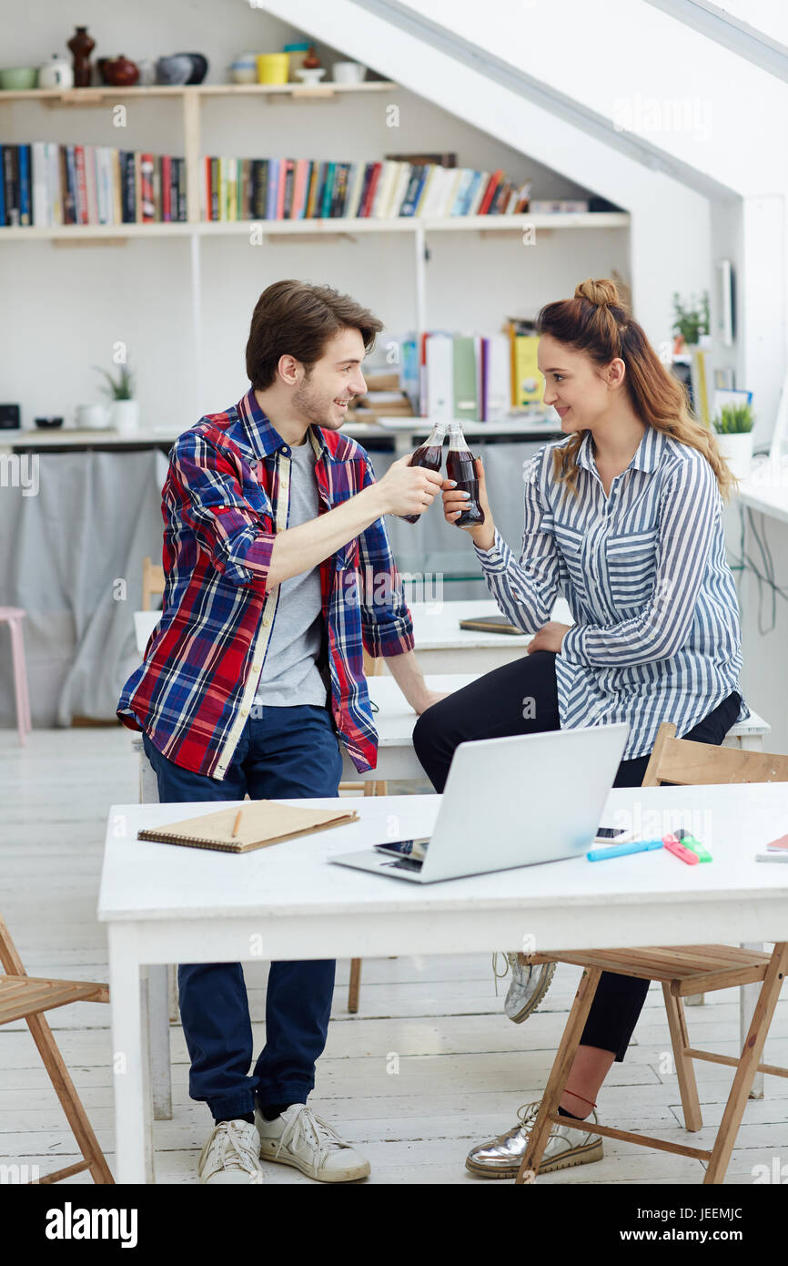 Two happy students cheering with bottles of soft drinks Stock Photo - Alamy