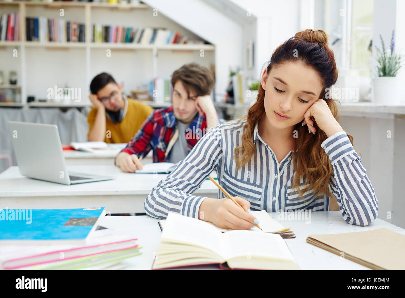 Young student making notes while reading book Stock Photo - Alamy