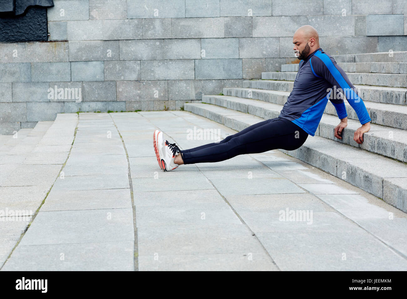 Active man doing physical exercise on staircase in urban environment ...