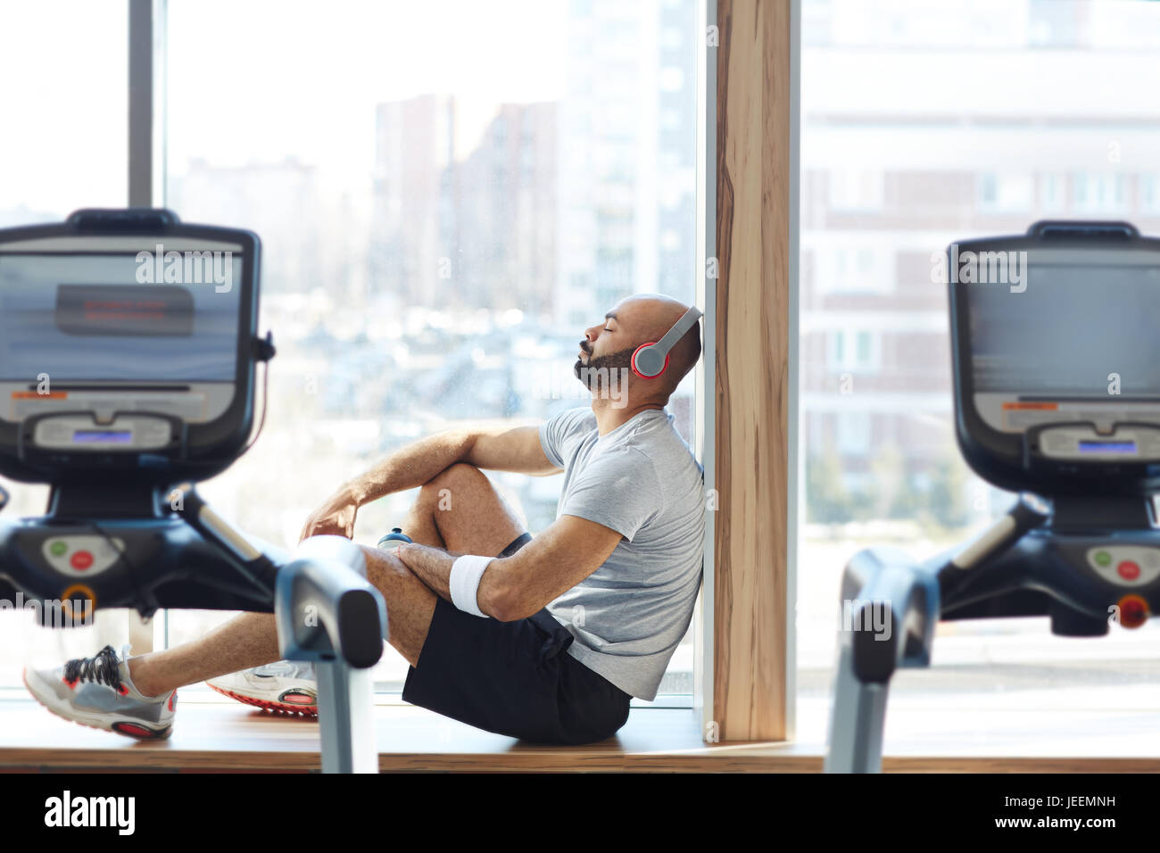 Relaxed man sitting on window-sill after training in gym Stock Photo ...