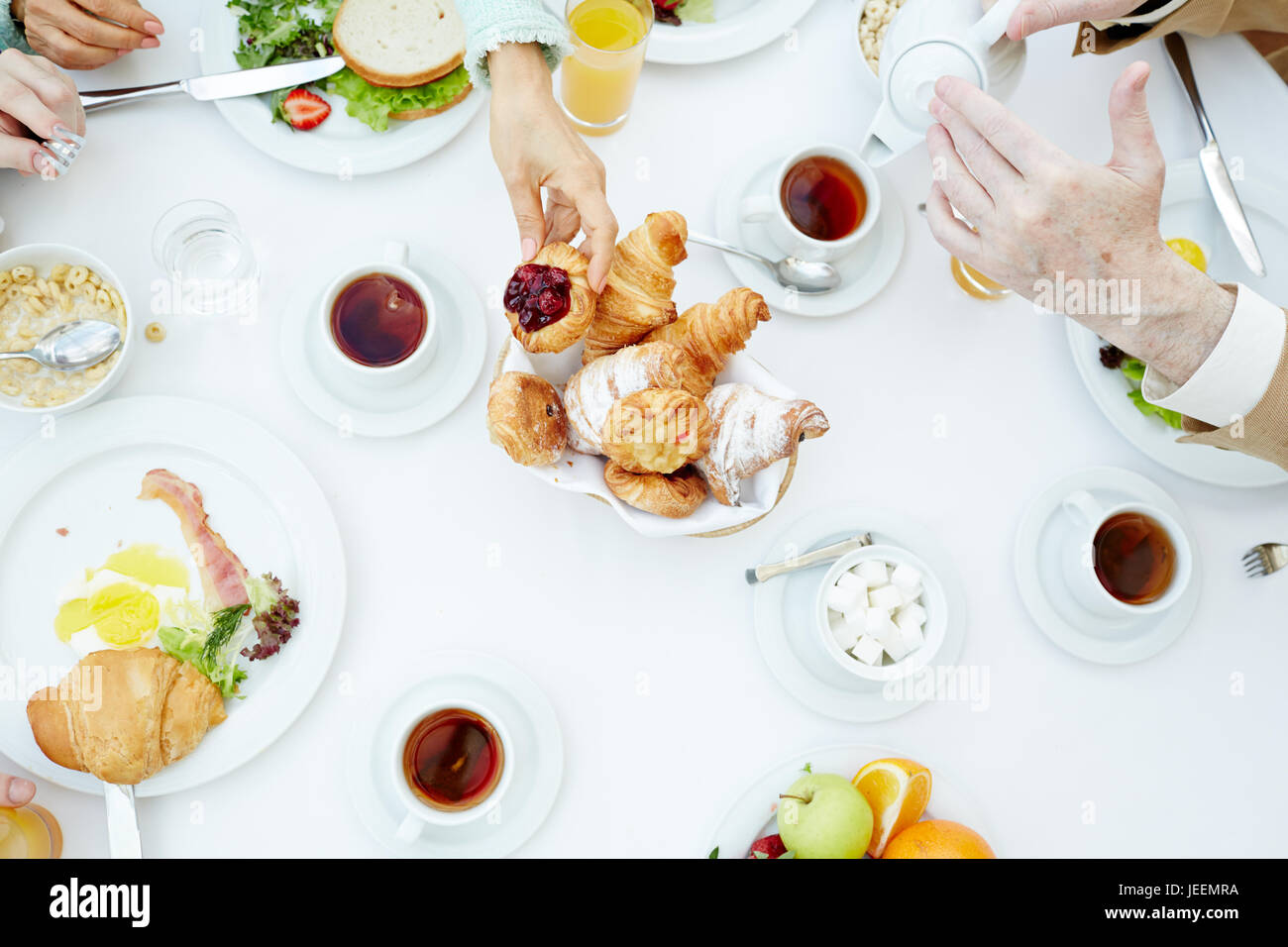 Human hand taking sweet bun during family breakfast Stock Photo - Alamy