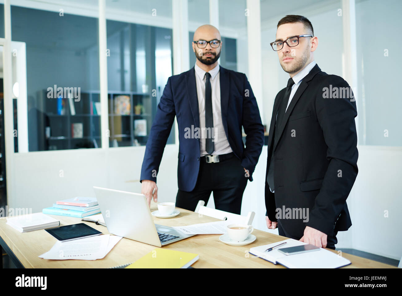 Serious businessman and his co-worker looking at camera Stock Photo - Alamy