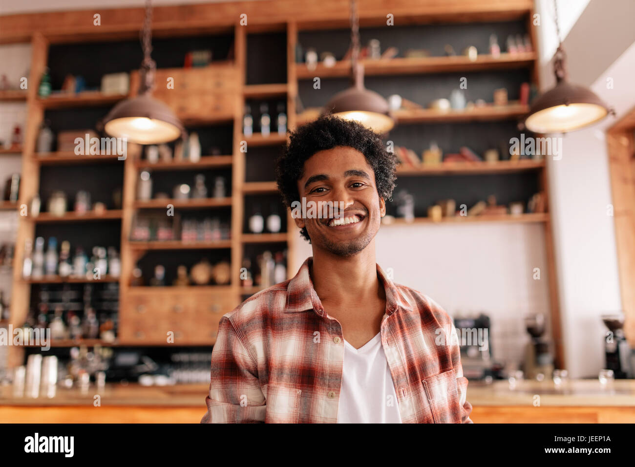 Portrait of happy young man standing in a cafe bar. Handsome young guy ...