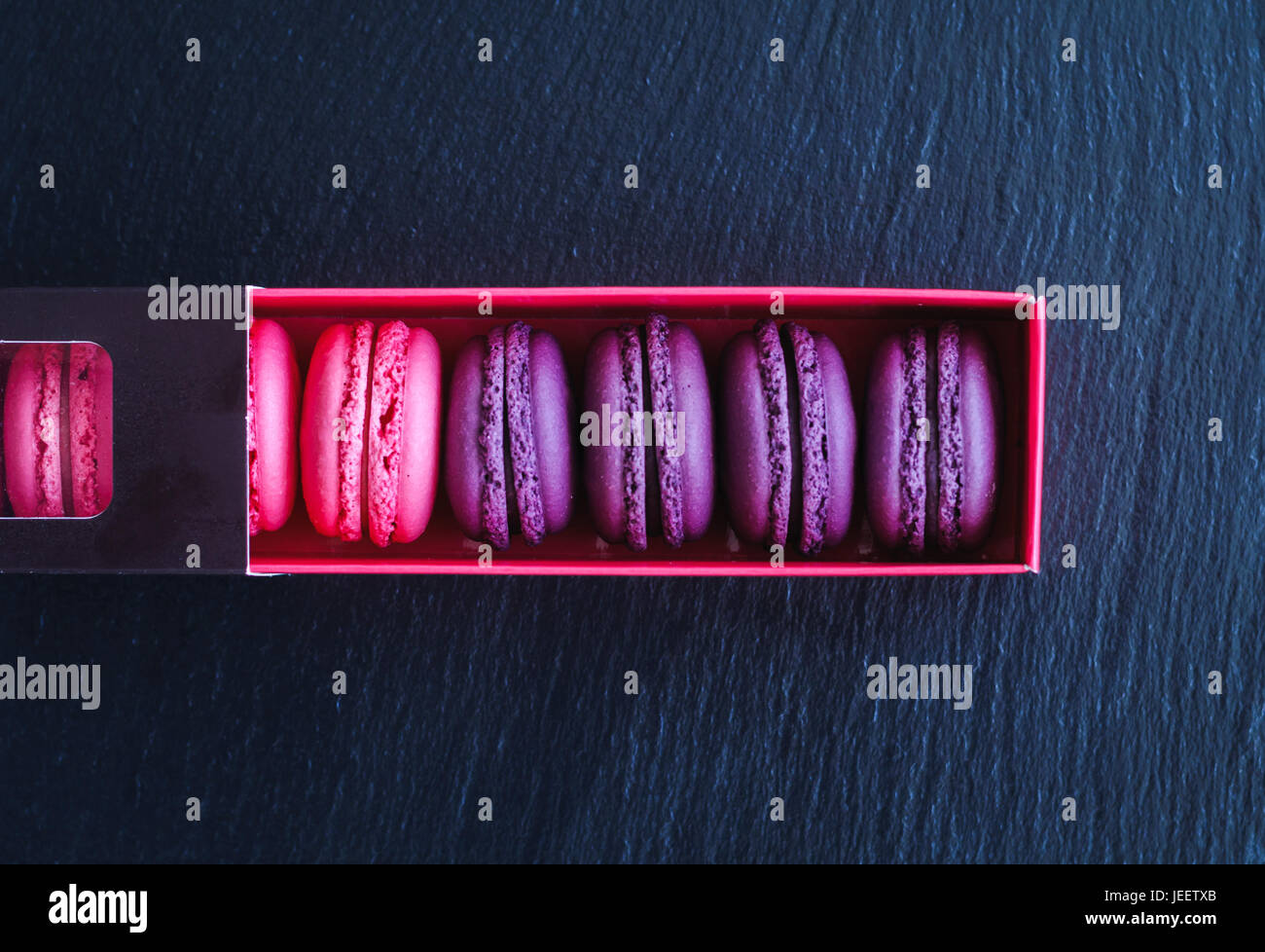 pink macaroons with blueberries on black background Stock Photo - Alamy