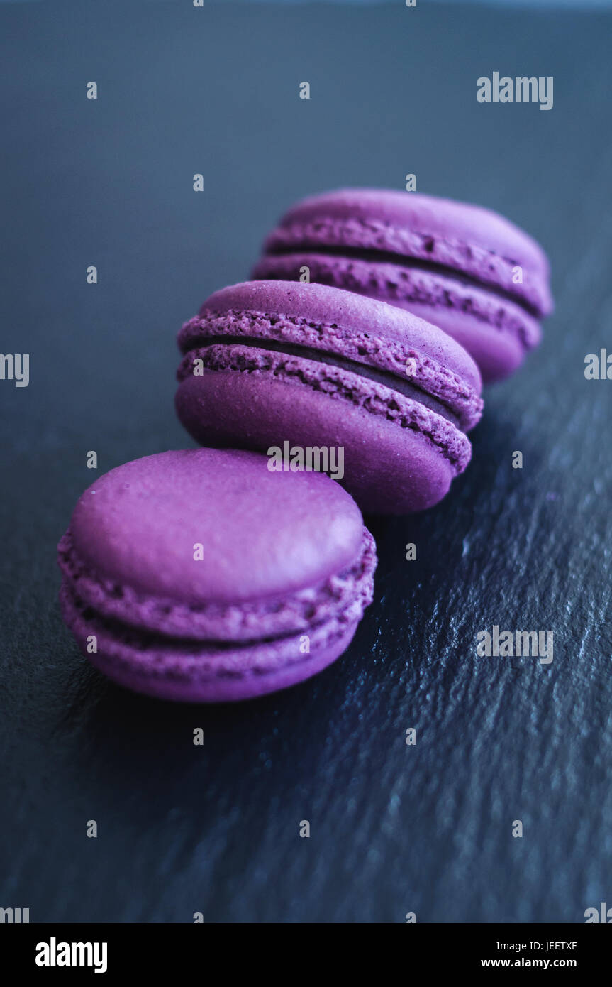 pink macaroons with blueberries on black background Stock Photo - Alamy